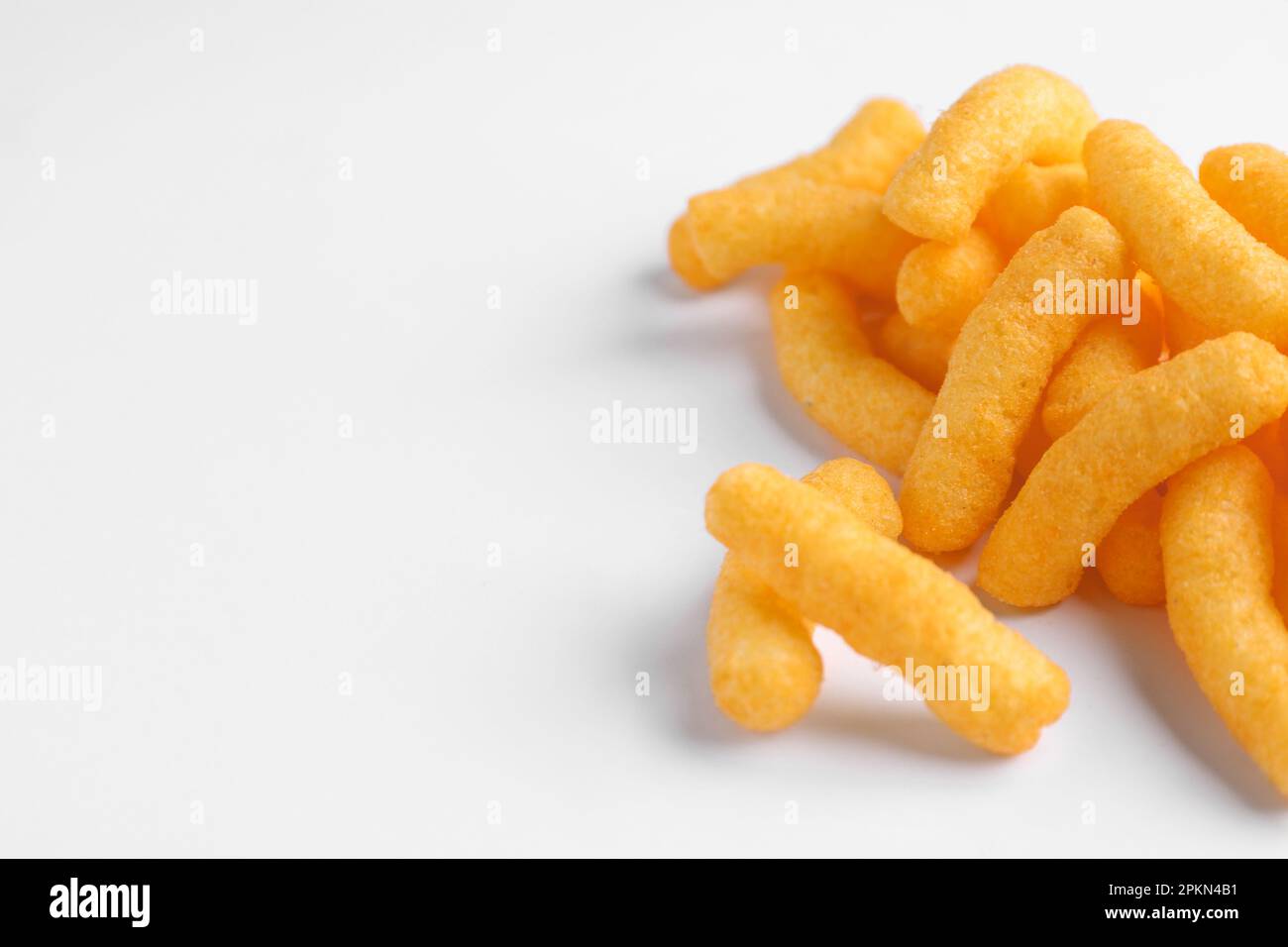 Heap of tasty cheesy corn puffs on white background, space for text ...