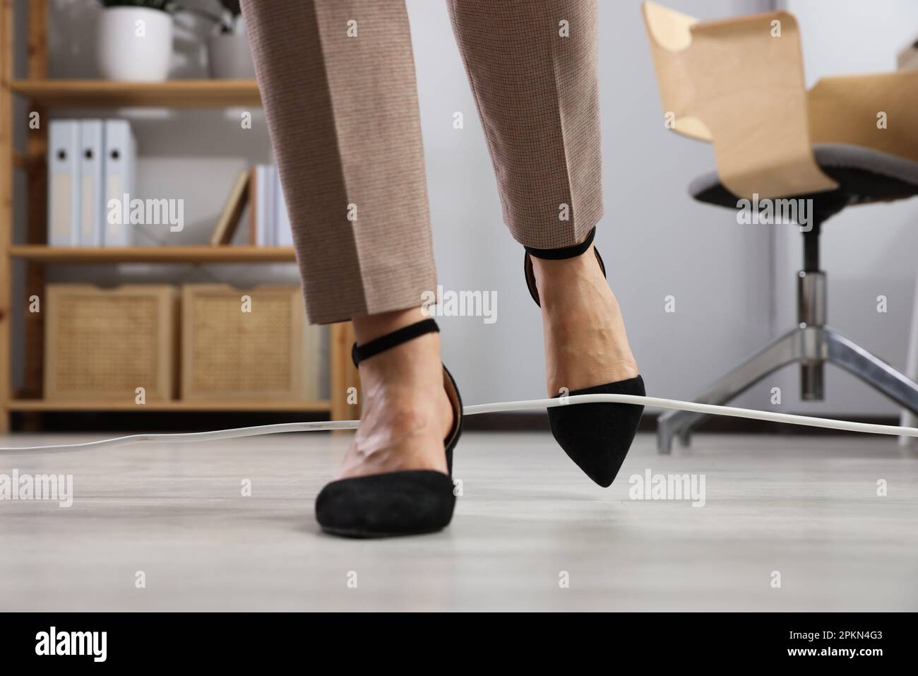 Woman tripping over cord in office, closeup Stock Photo - Alamy