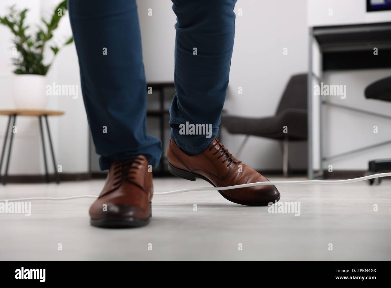 Man tripping over cord in office, closeup Stock Photo - Alamy
