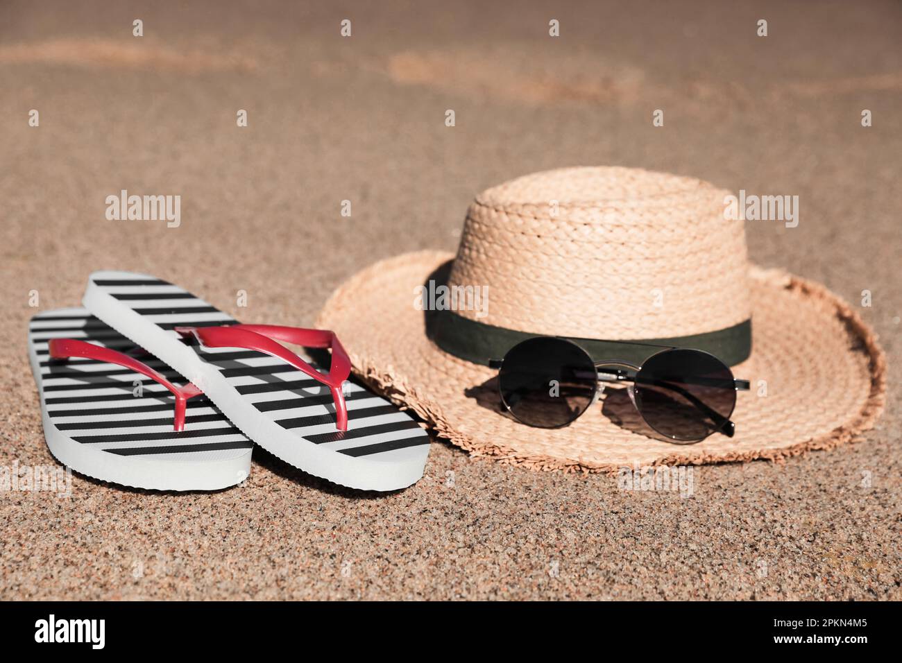 Striped flip flops, straw hat and sunglasses on sandy seashore Stock ...