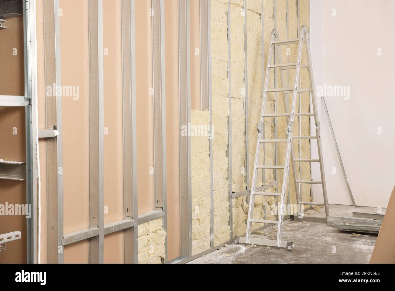 Ladder near wall with metal studs and insulation material indoors Stock ...