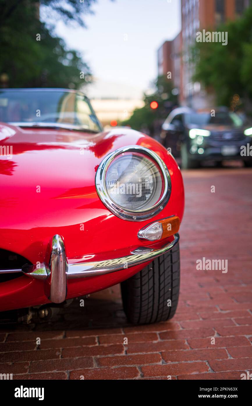 An antique red Jaguar car from the mid-20th century is parked on a city ...
