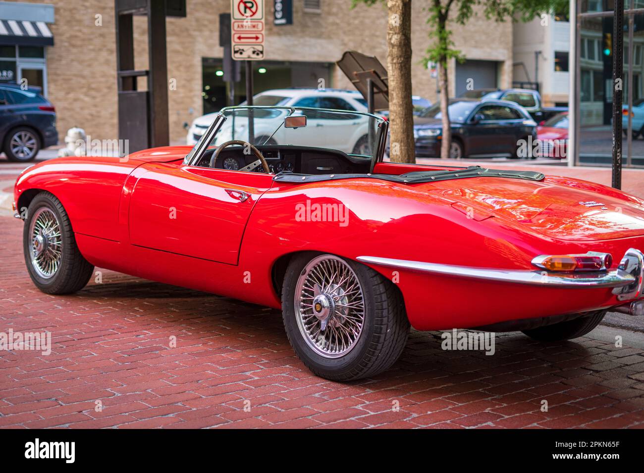 An antique red Jaguar car from the mid-20th century is parked on a city ...