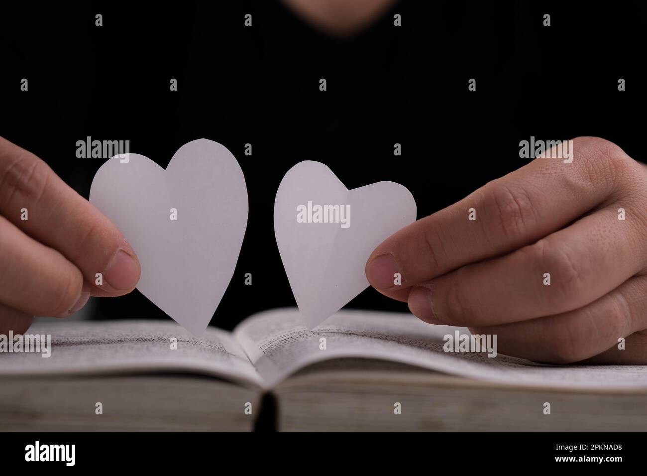 Book with open pages and heart shaped paper. Woman hand holding heart ...