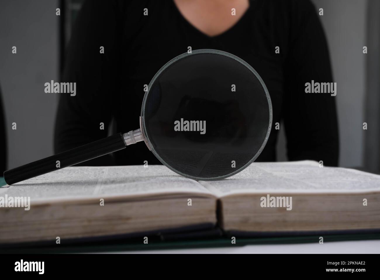 Magnifying glass over open book on table. Education and research ...