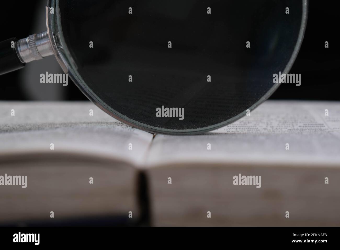 Magnifying glass over open book on table. Education and research ...