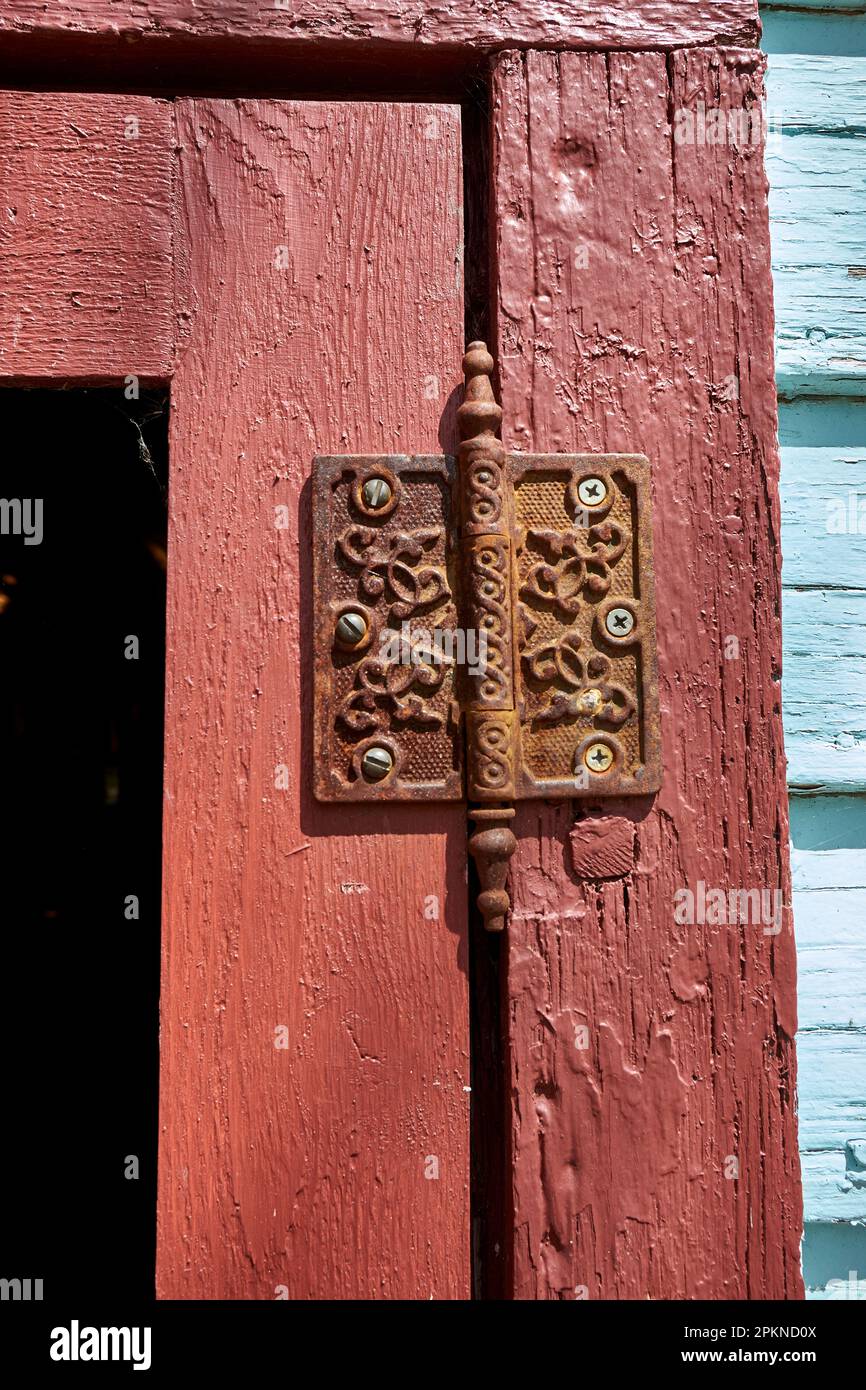 A rusted antique hinge attached to a red wooden door Stock Photo - Alamy