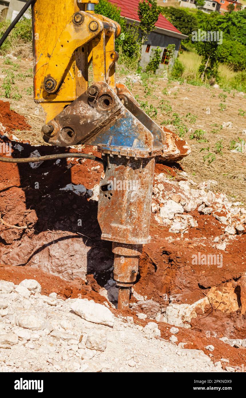 A heavy-duty jack-hammer is used to break embedded rock in a trench for ...
