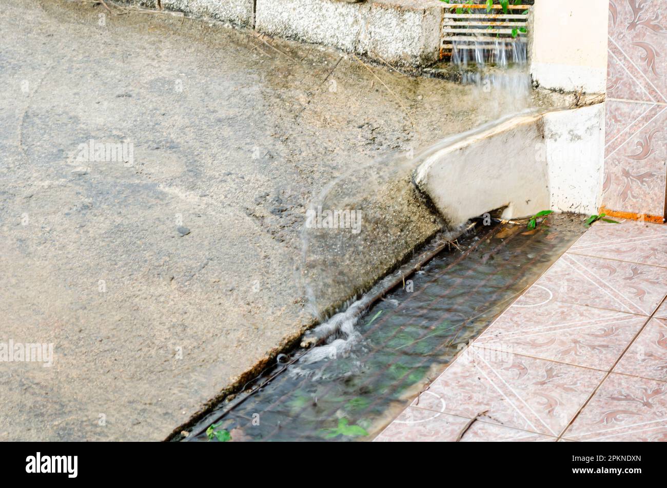 It is raining and excess water flows into a trench at the front of a ...