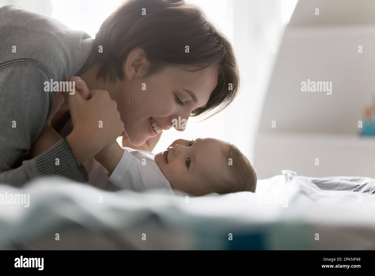 Happy cheerful new mom caressing adorable baby lying on back Stock ...