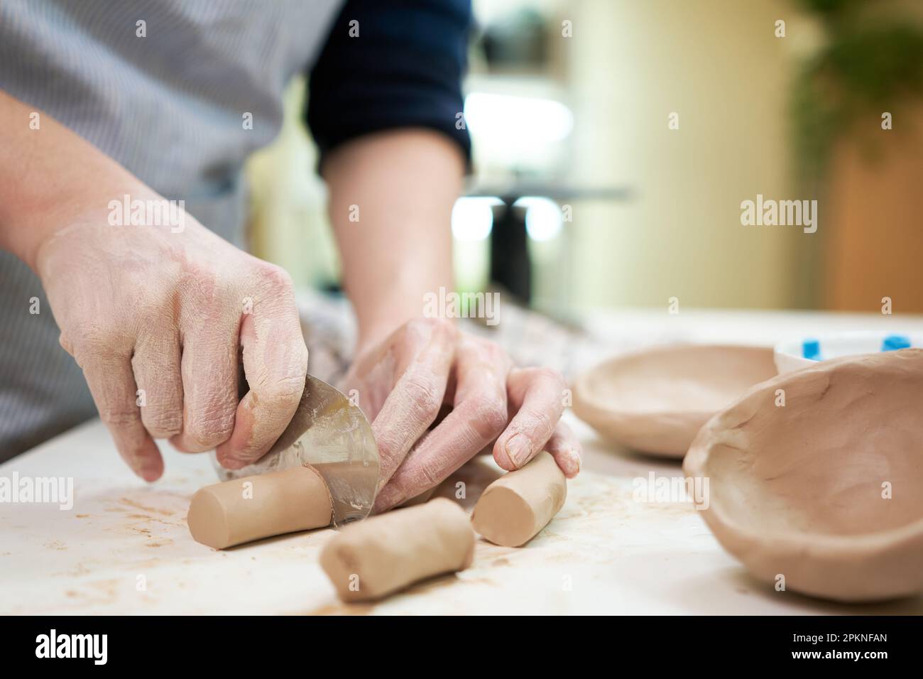 Woman cutting clay with blade standing behind table in studio Stock ...