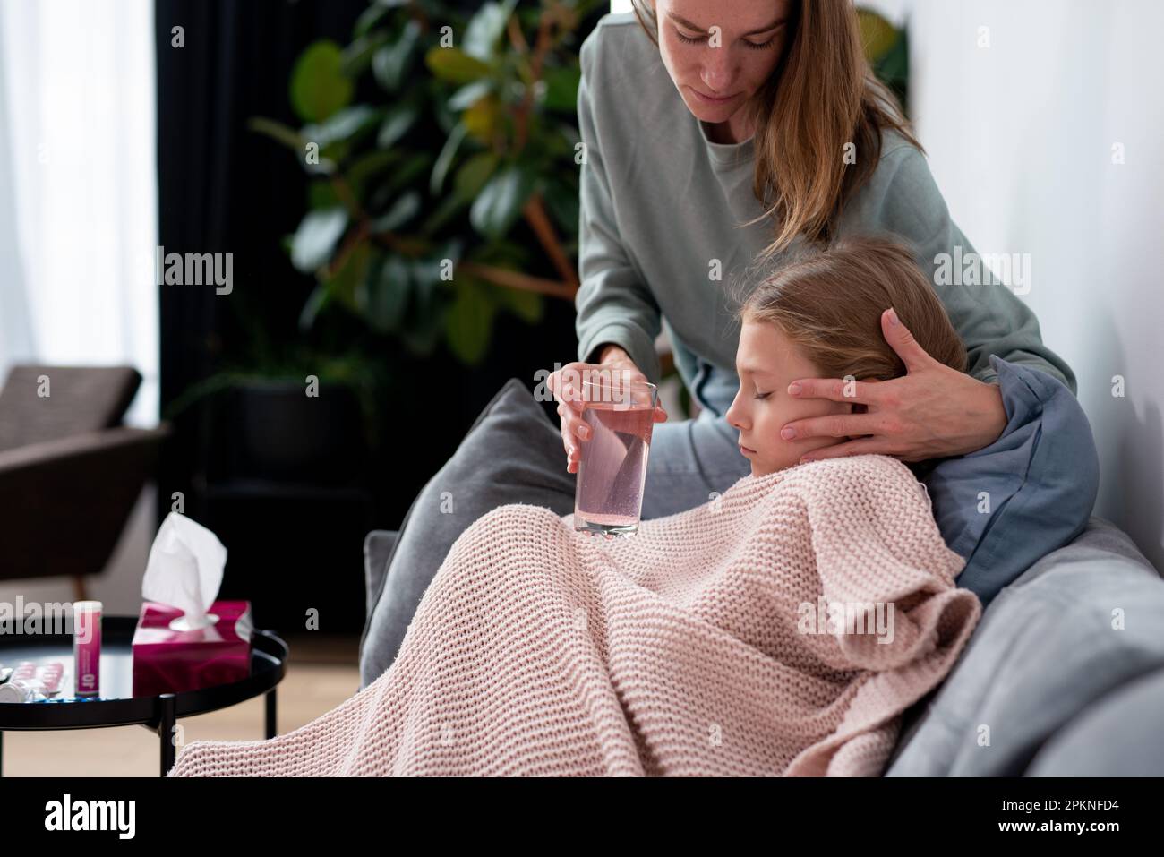 Mom gives her daughter a drink when she has a cold Stock Photo - Alamy