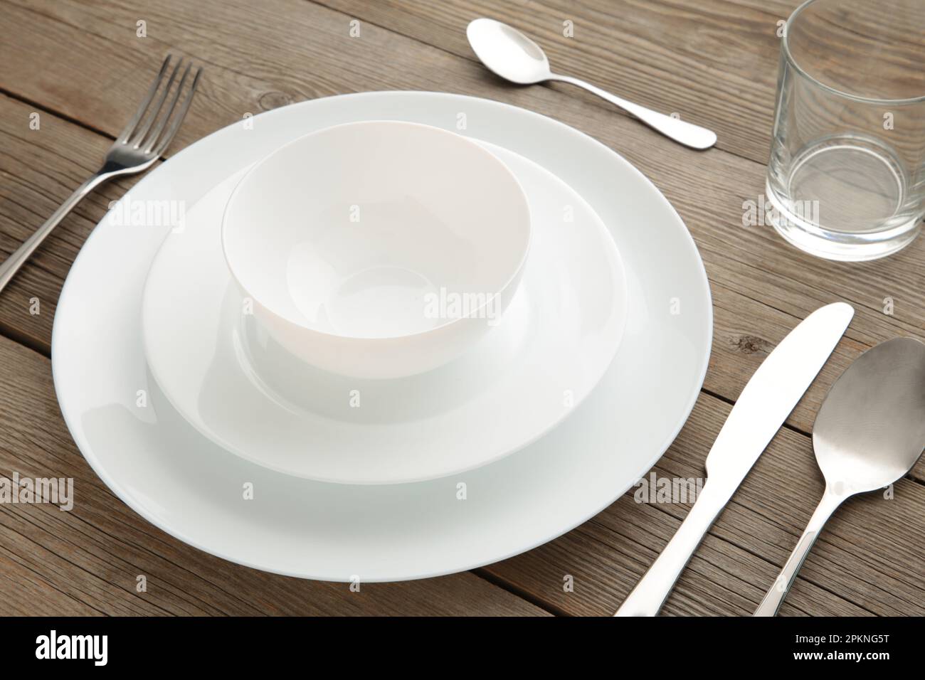 Table setting with white plates, glass, and cutlery - fork, spoon and ...