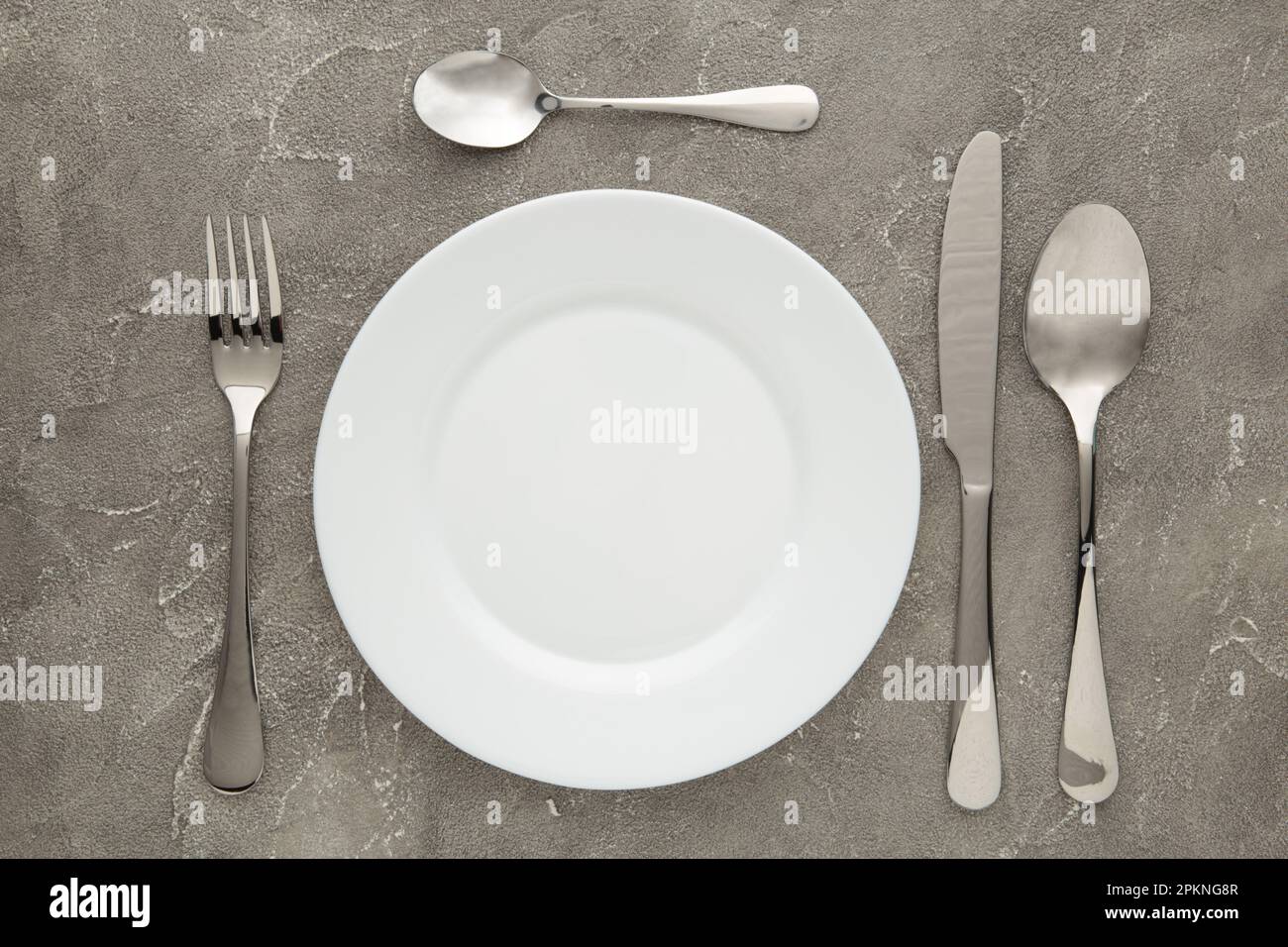 Table setting with white plates, and cutlery - fork, spoon and knife ...