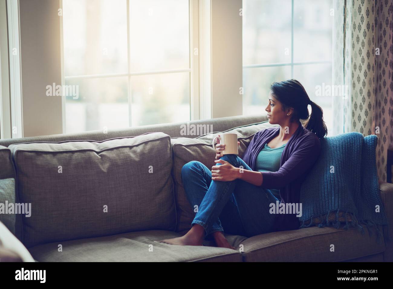 Less chaos, more comfort. a young woman relaxing on the sofa with a cup ...