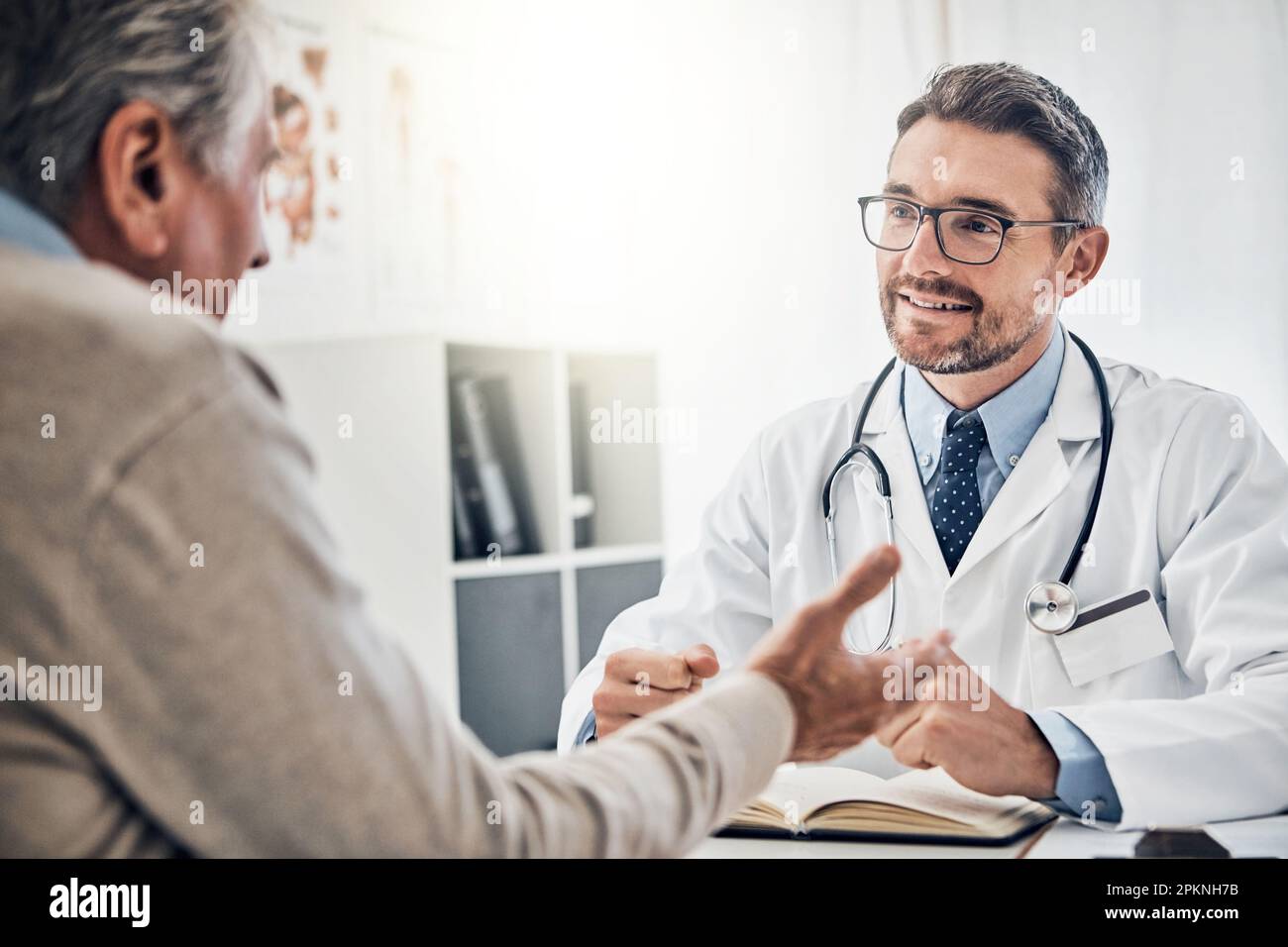 Describing his symptoms in detail. a friendly doctor consulting with a ...
