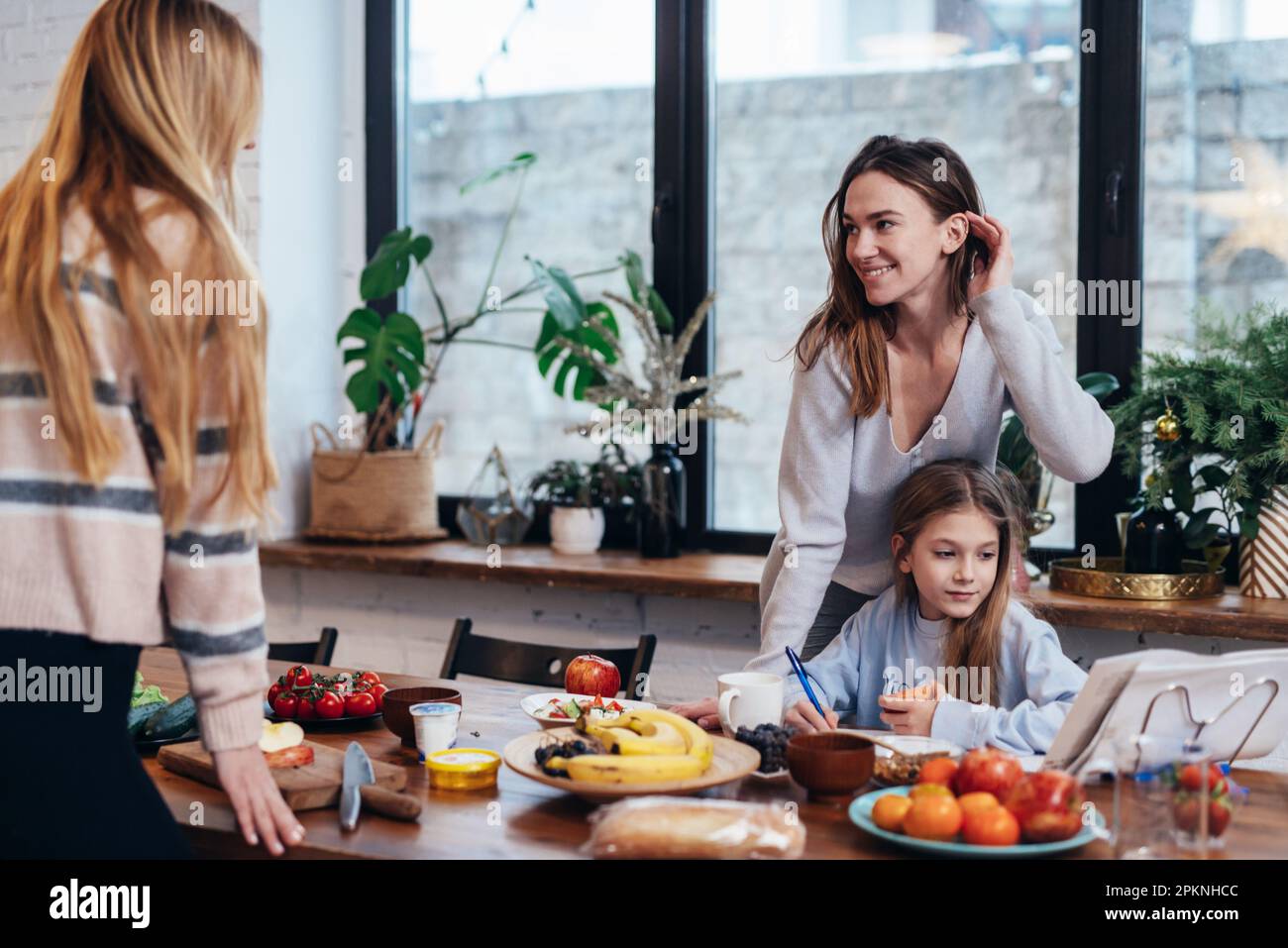 Young women set the table, girl does her homework Stock Photo - Alamy