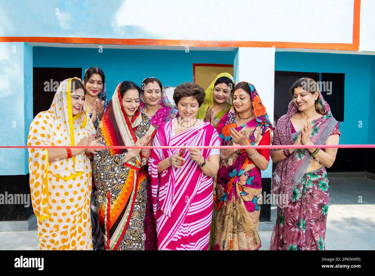 Indian business woman in sari cutting red ribbon while colleagues are ...