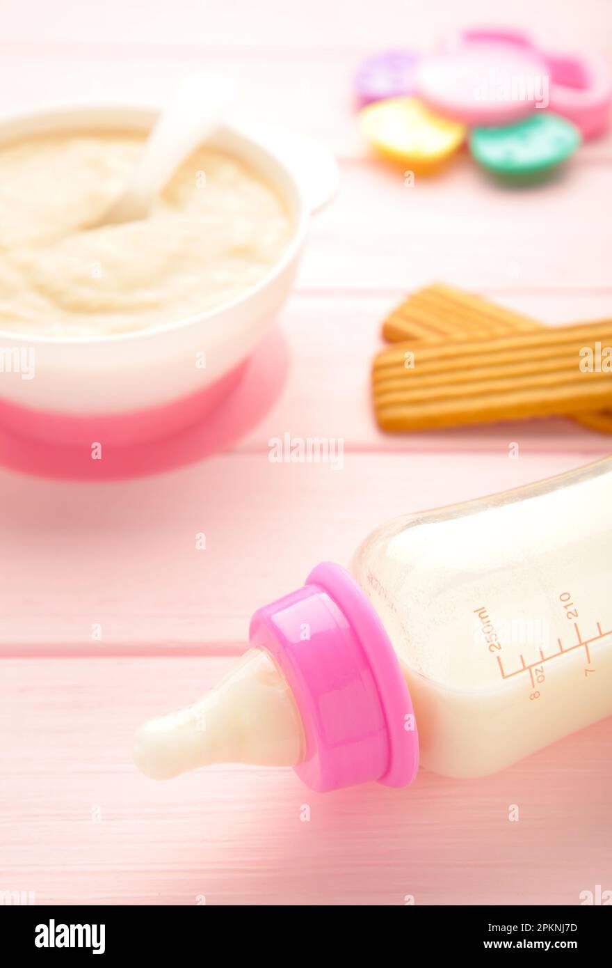 Milk and bowl with porridge for baby on pink background. Vertical foto ...
