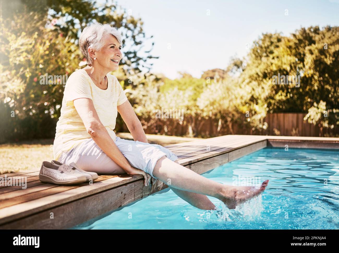 The coolest way to spend summer. a happy senior woman dipping her feet ...