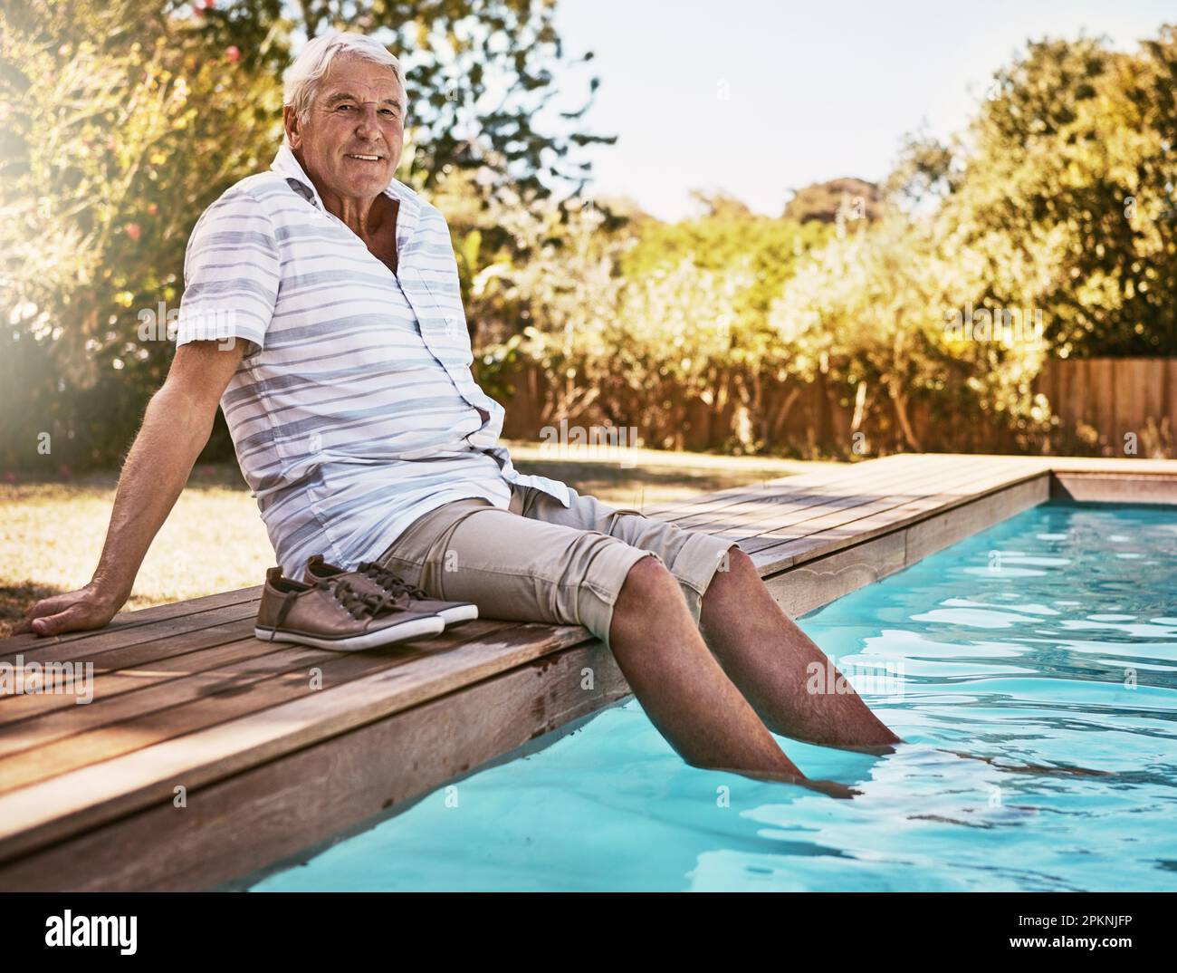 The sun is out and I feel good. a happy senior man dipping his feet in ...