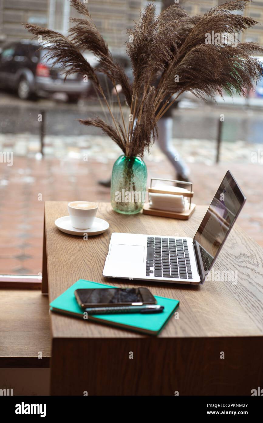 Workplace in cafe. Laptop, note book and coffee near window in cafe ...