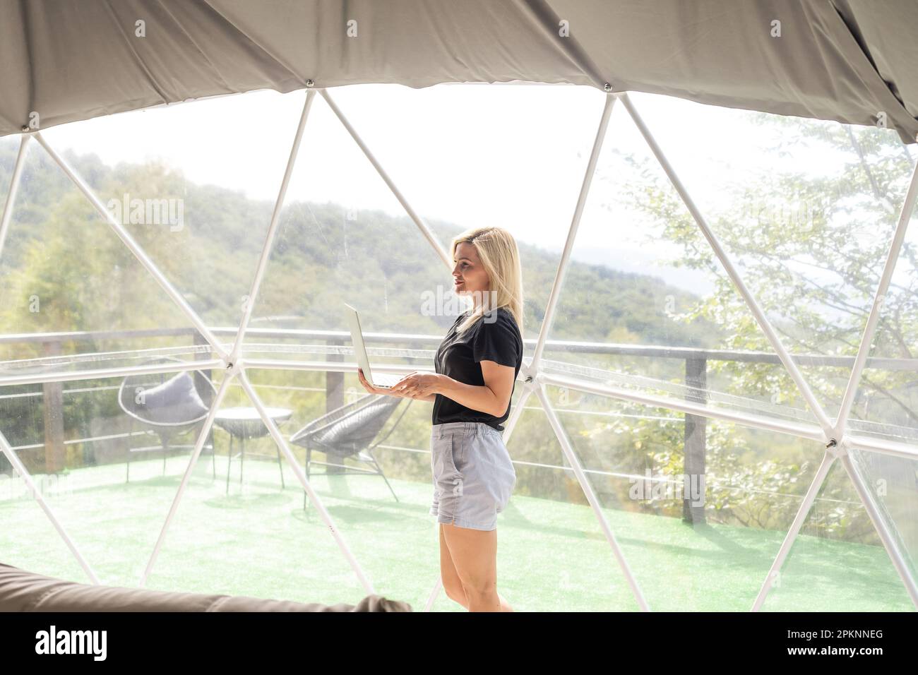 Woman working on laptop geo dome tents. Green, blue background. Cozy, camping, glamping, holiday ...