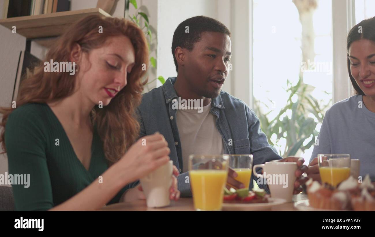 Happy friends eating breakfast together at home Stock Photo - Alamy