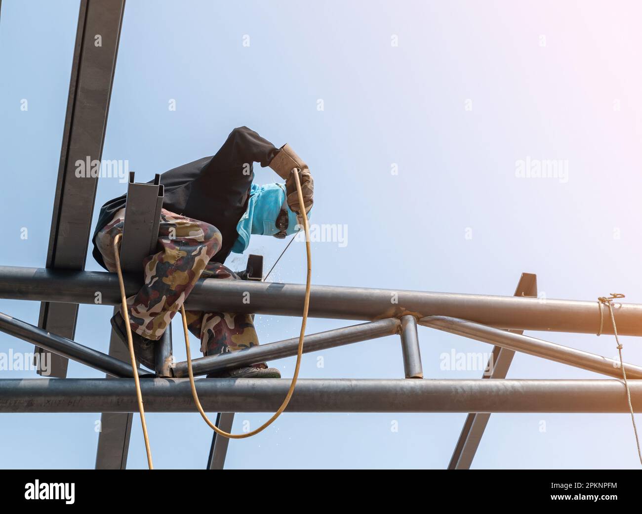 A welder working on a high rooftop for a new building Stock Photo - Alamy