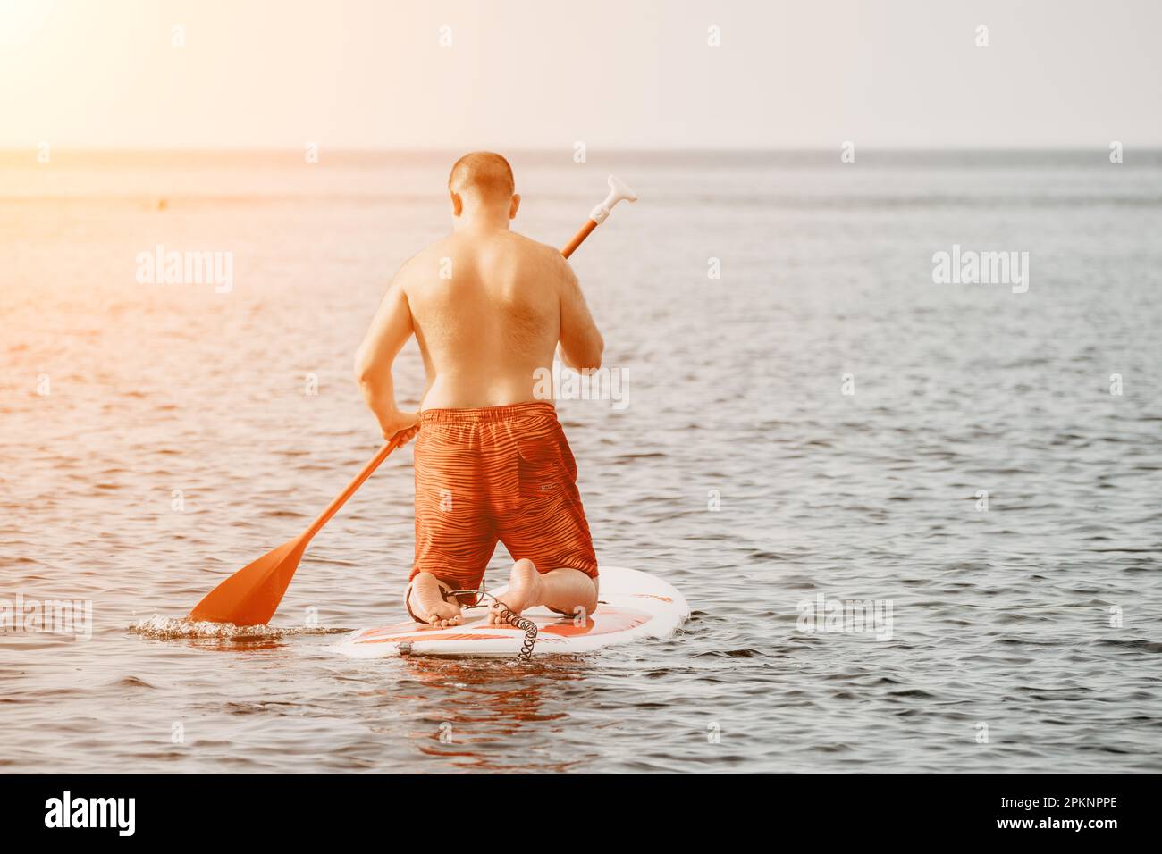 Active mature male paddler with his paddleboard and paddle on a sea at ...