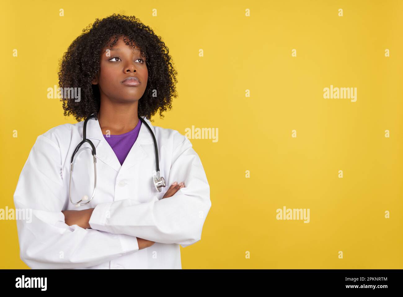 Proud afro female doctor looking up with arms crossed Stock Photo - Alamy