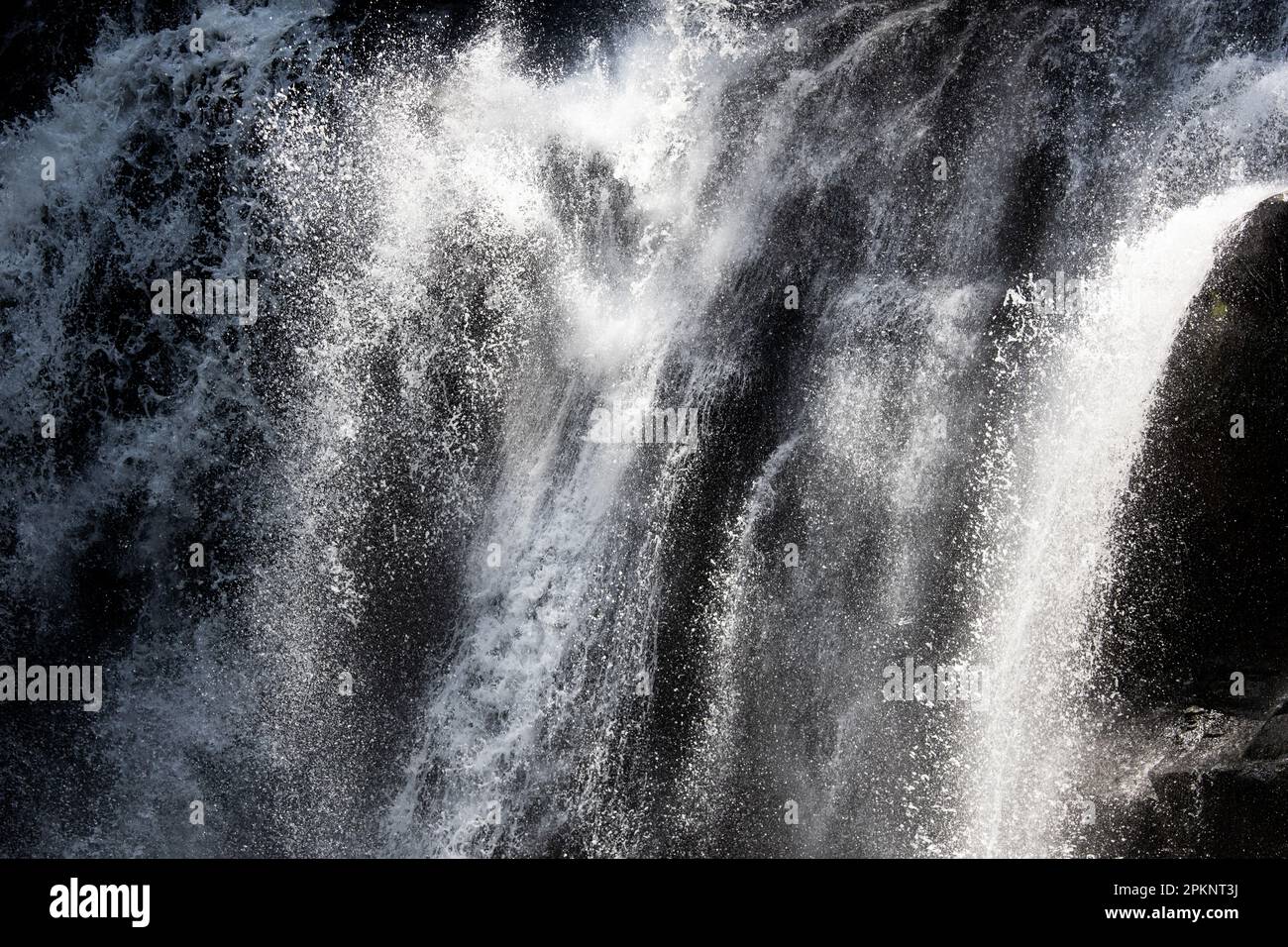 Tropical waterfall with water drops and sprays falling from a cliff in ...