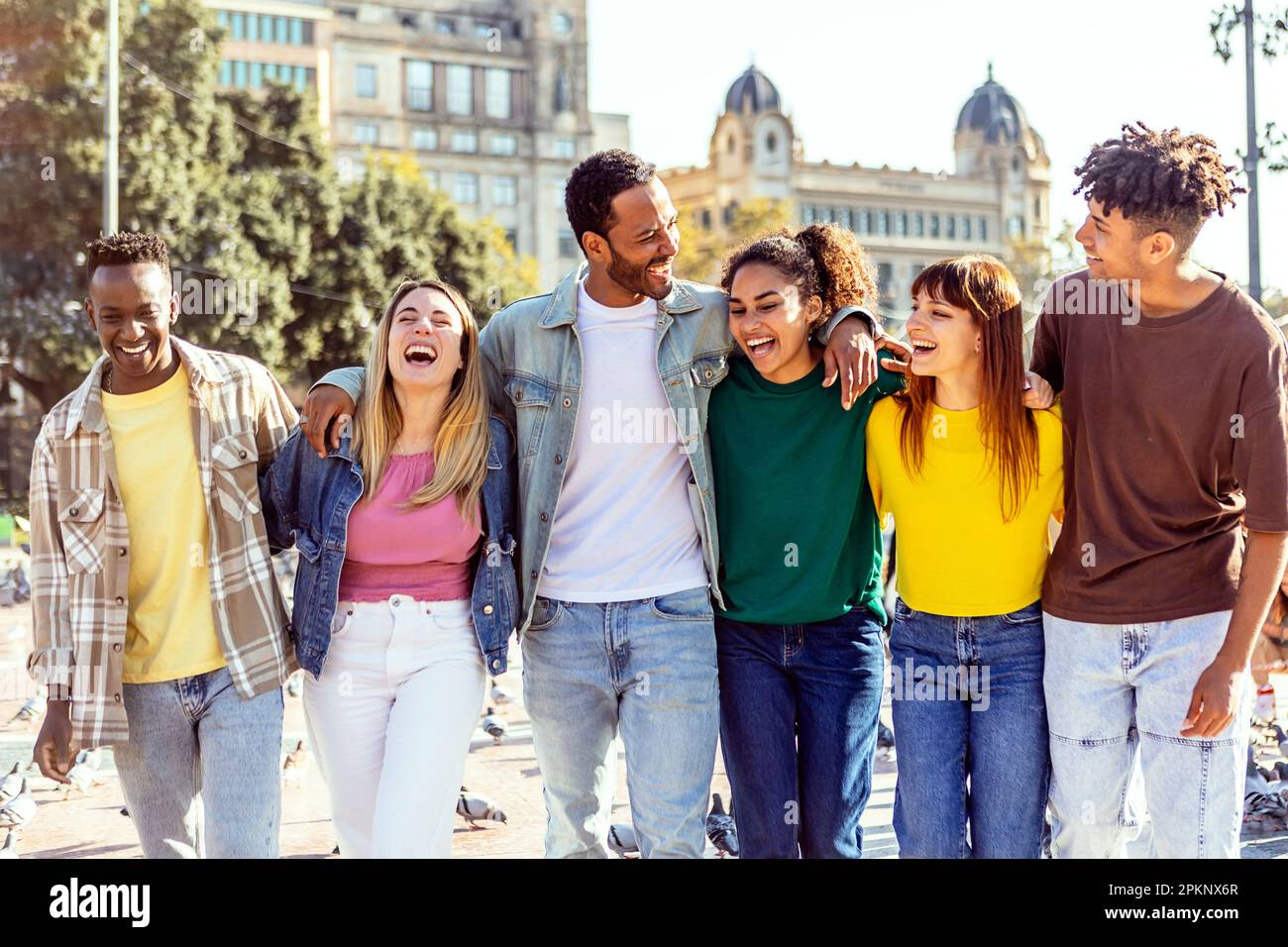 Group of six multiethnic happy friends hugging each other walking in ...