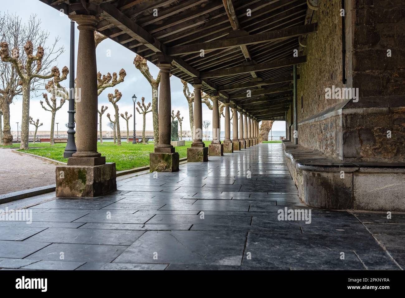 Passageway with arched doors and wooden roof with old stone columns in ...
