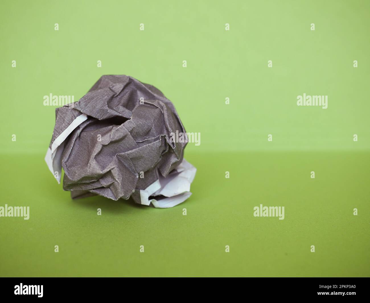 crumpled paper ball over a green background Stock Photo - Alamy