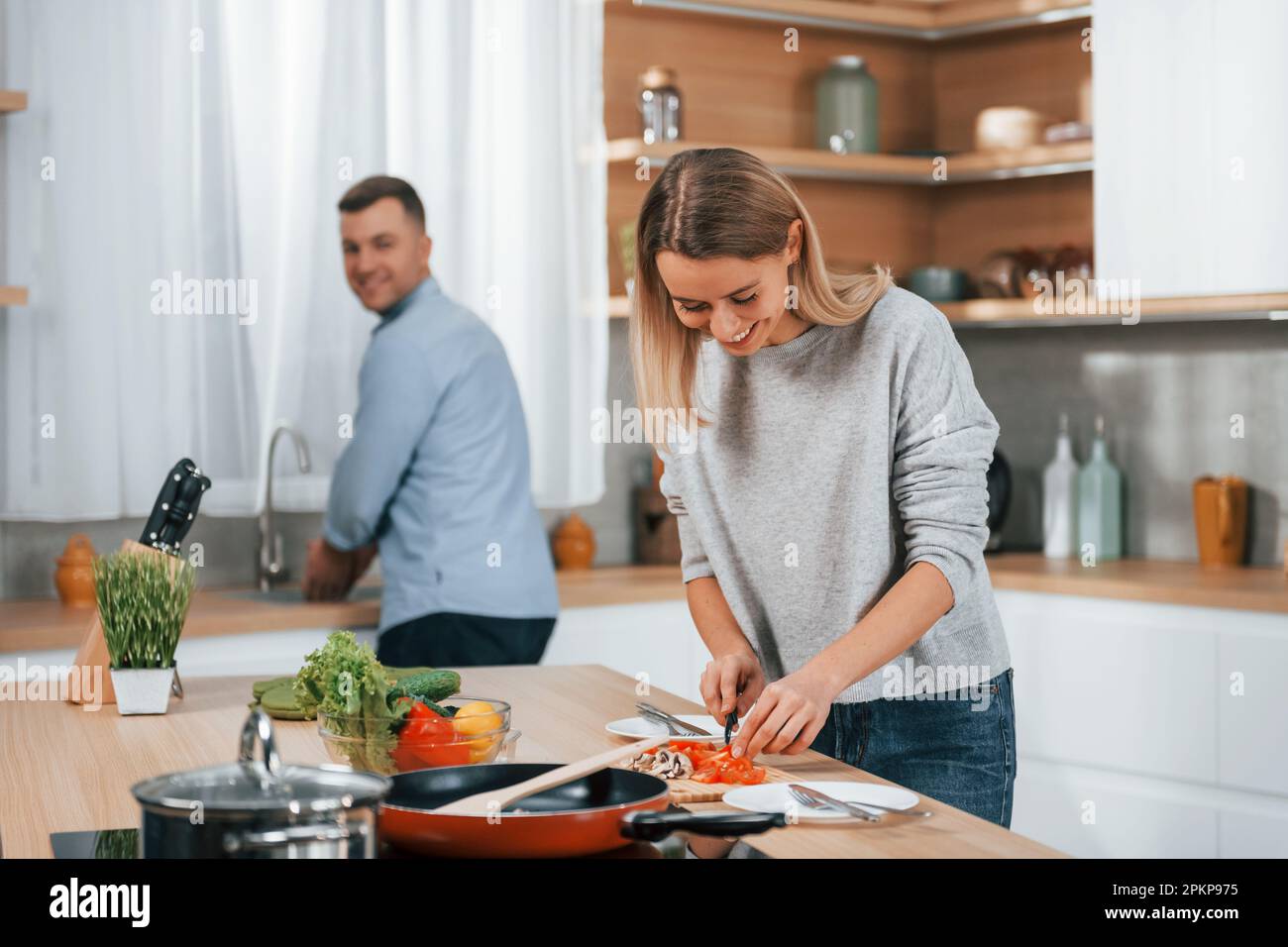 Positive emotions. Couple preparing food at home on the modern kitchen ...