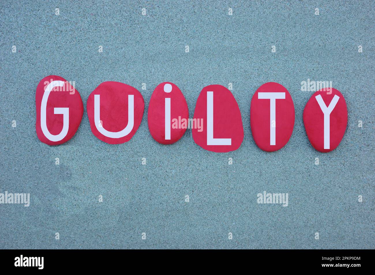 Guilty word composed with hand painted red hand painted stone letters ...