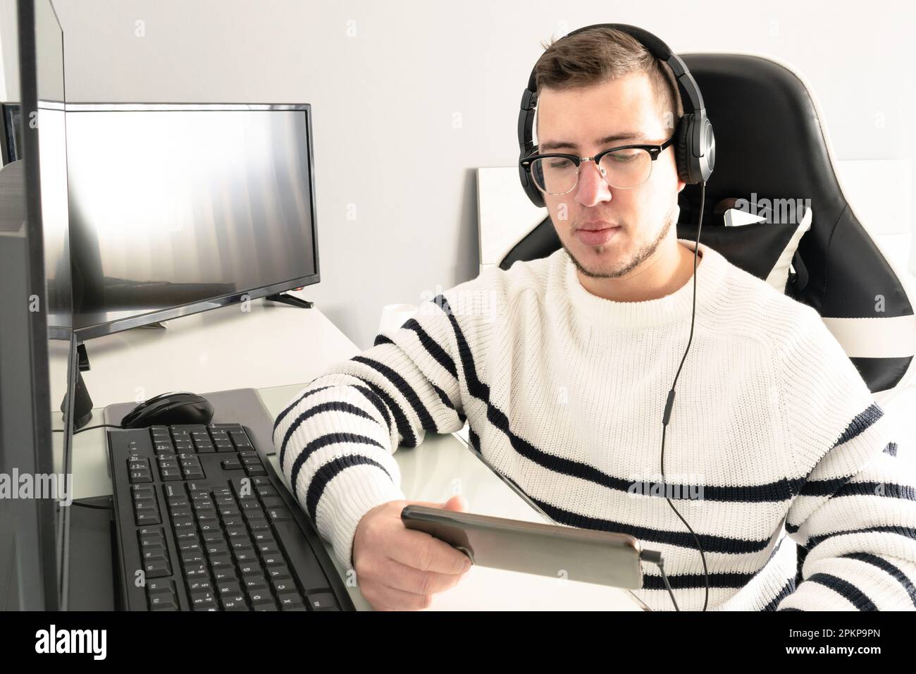 young man sitting on chair gaming relaxed with headphones watching ...
