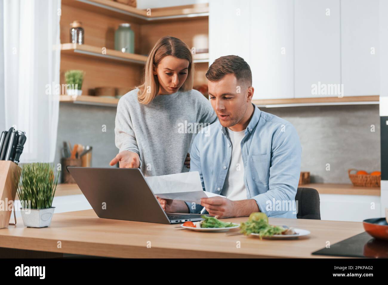 Using internet. Couple preparing food at home on the modern kitchen ...