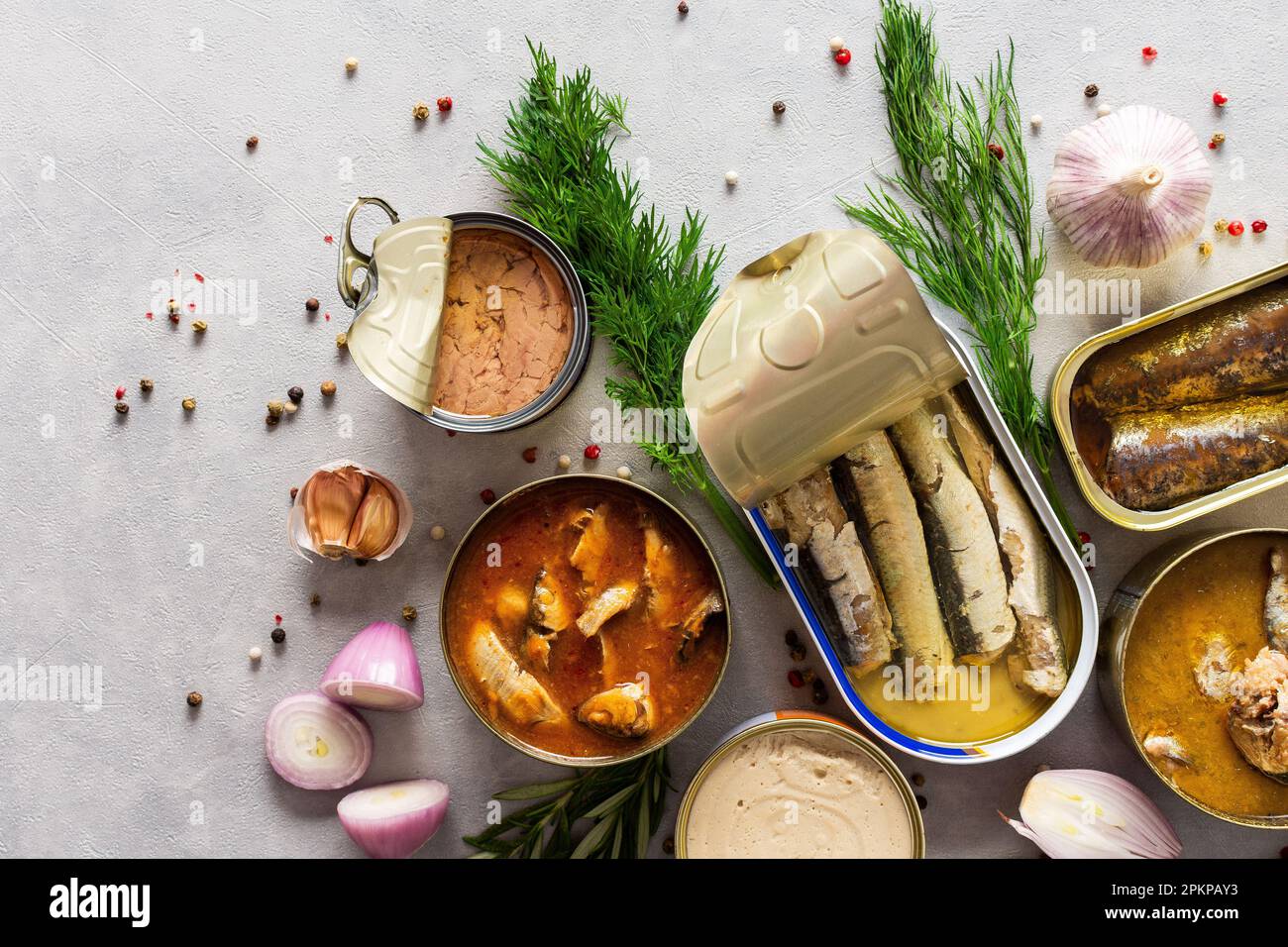 Different open tin cans with canned fish among spices and herbs, canned ...