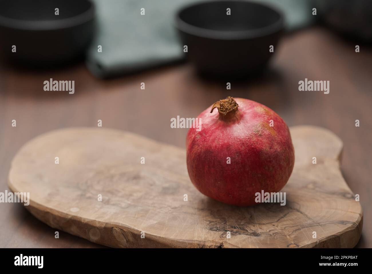 Ripe small pomegrenate on olive wood board, shallow focus Stock Photo ...