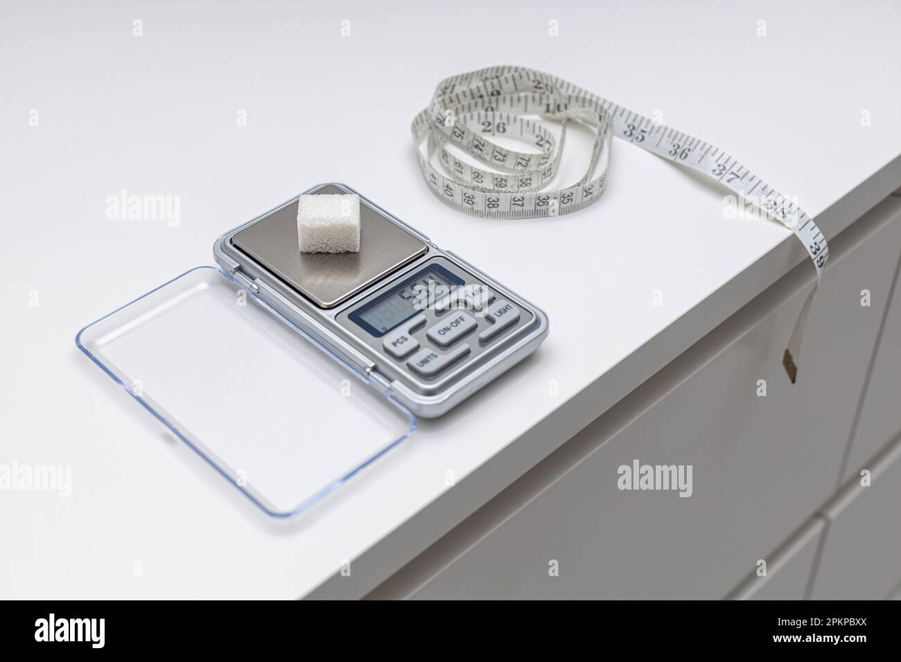 a sugar cube lies on a small scale. white sugar cubes. sugar control ...