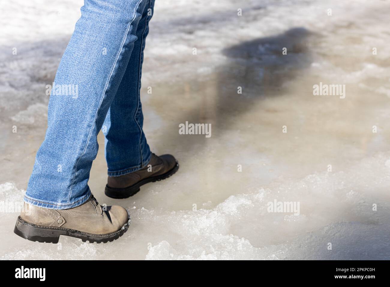 man walking on ice in the park. a woman walks through a puddle in ...