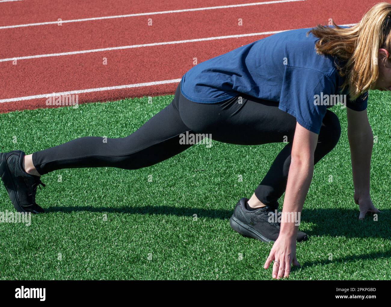 Side view of a high school teanage girl stretching before track ...
