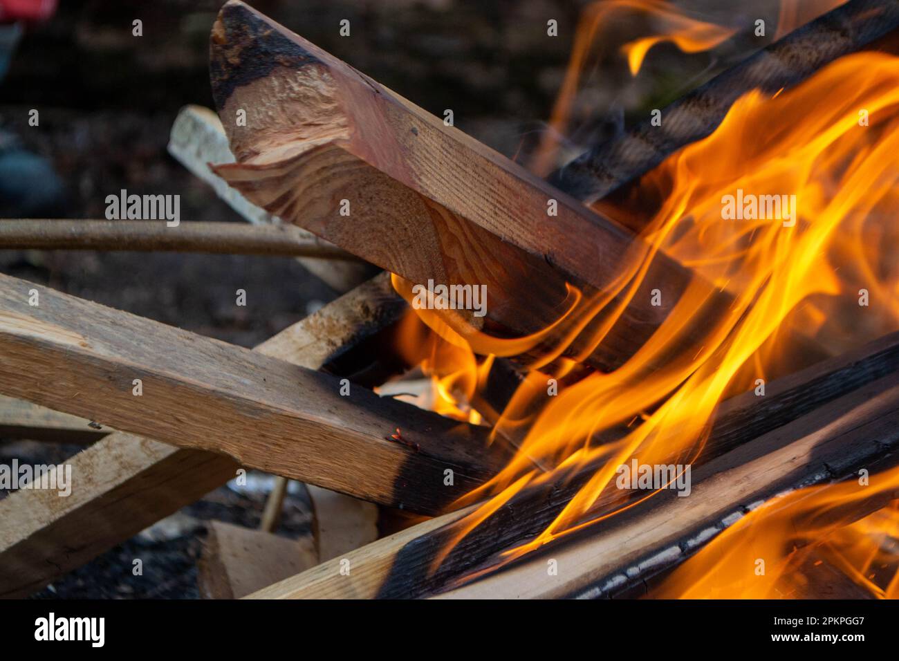 A fire burns in a campfire with a red fire in the background. High ...