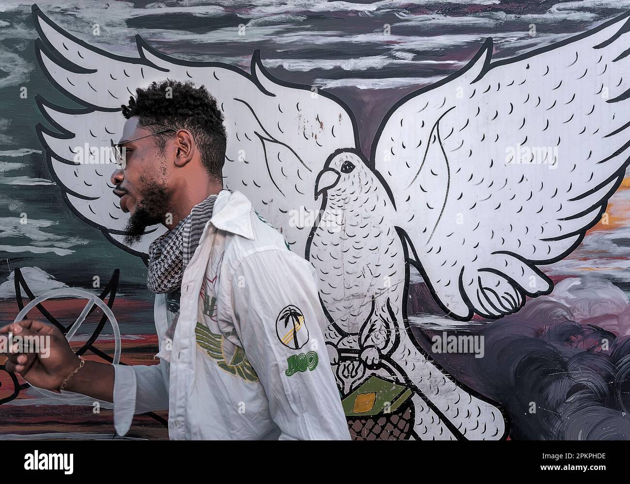 Harun Suluhu walks past a nural of a peace dove in the old town of Lamu ...
