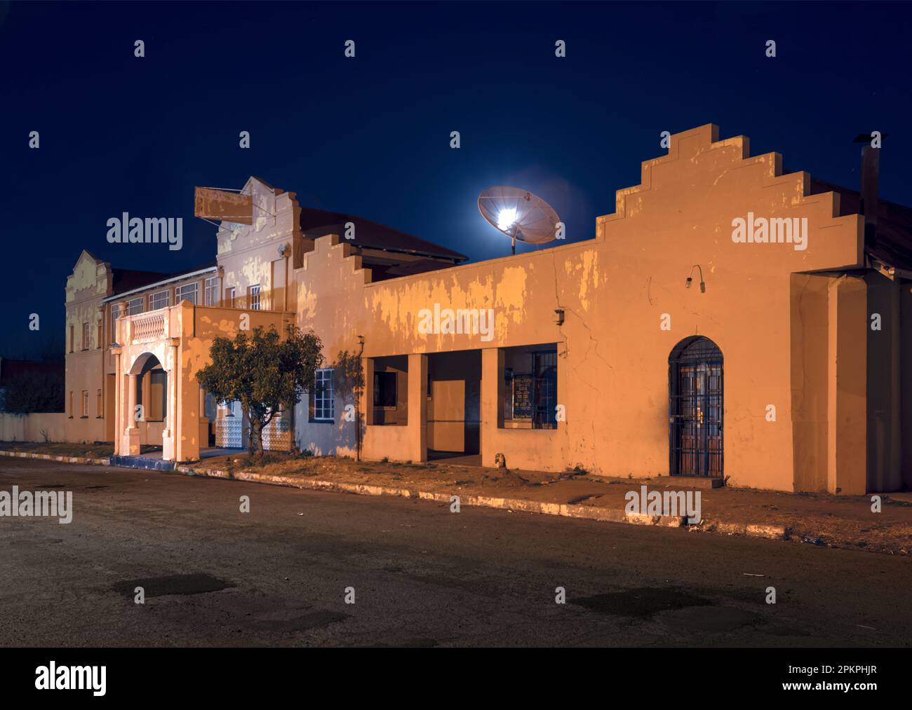 The full moon sets behind an antenna dish on the roof of the old ...