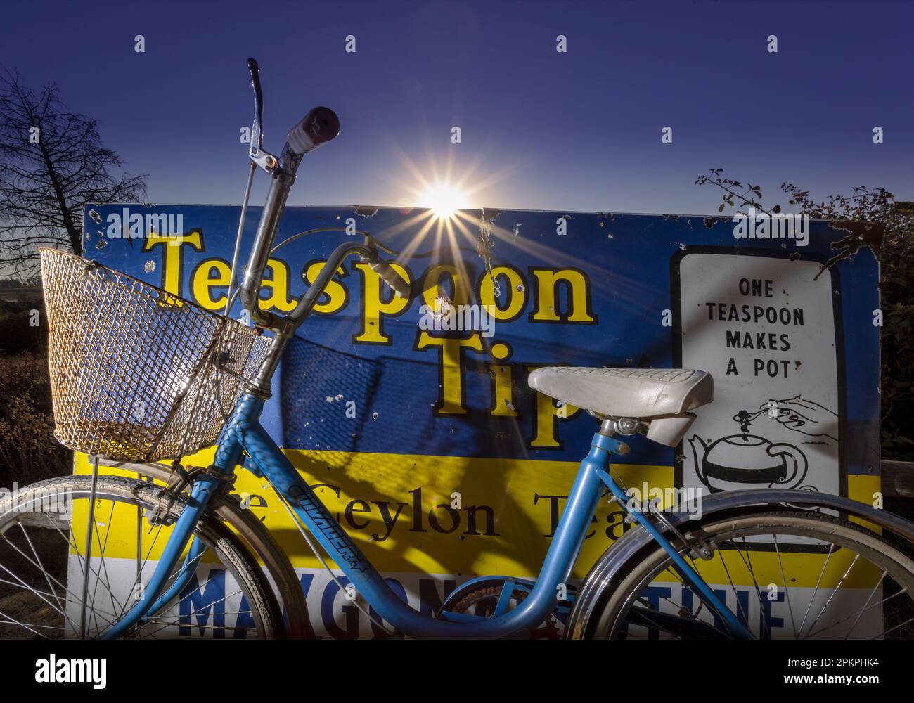 a bicycle stands against an old tea poster at the Cabin Farm stall near ...