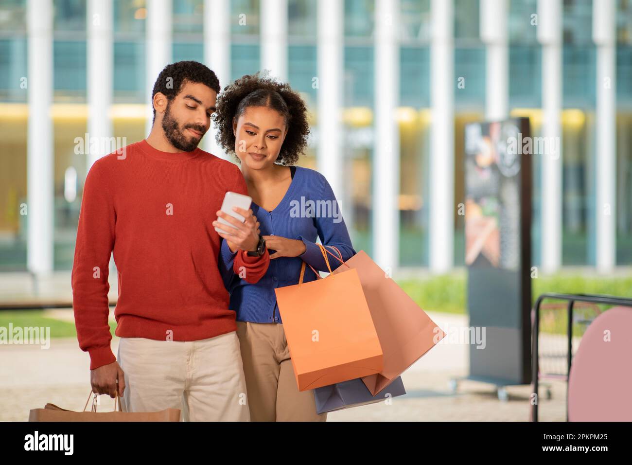 Happy Multicultural Couple Doing Shopping Using Cellphone Standing ...