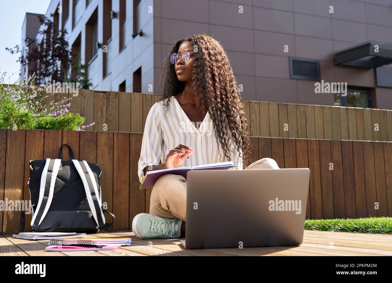 African female student writing notes elearning using laptop studying ...